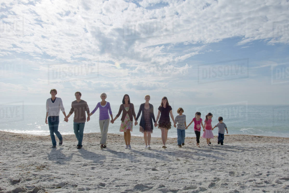 Group of people holding hands and walking together on beach - Stock ...